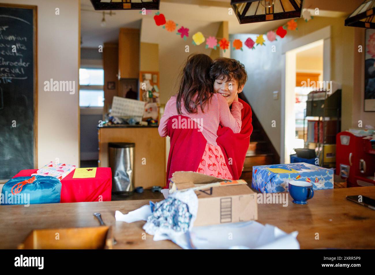 Two happy children hug at table with presents Stock Photo - Alamy
