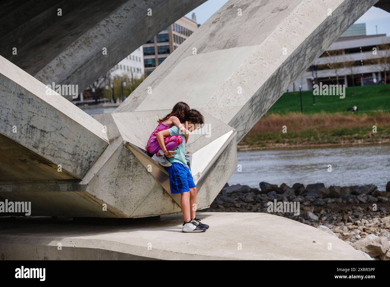 Little boy carries small girl off bridge piling Stock Photo - Alamy