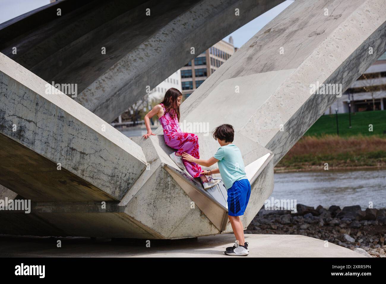 Young boy helps small girl down from bridge piling Stock Photo - Alamy