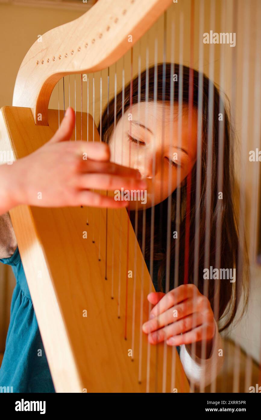 A little girl plays harp in patch of sunlight Stock Photo - Alamy