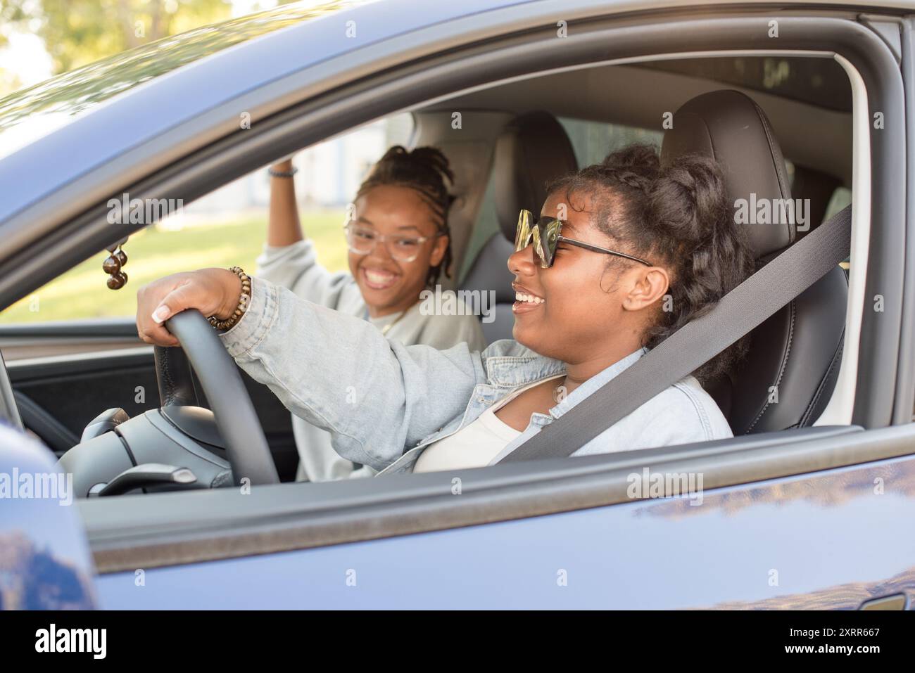 Young driver getting out of a car laughing Stock Photo - Alamy