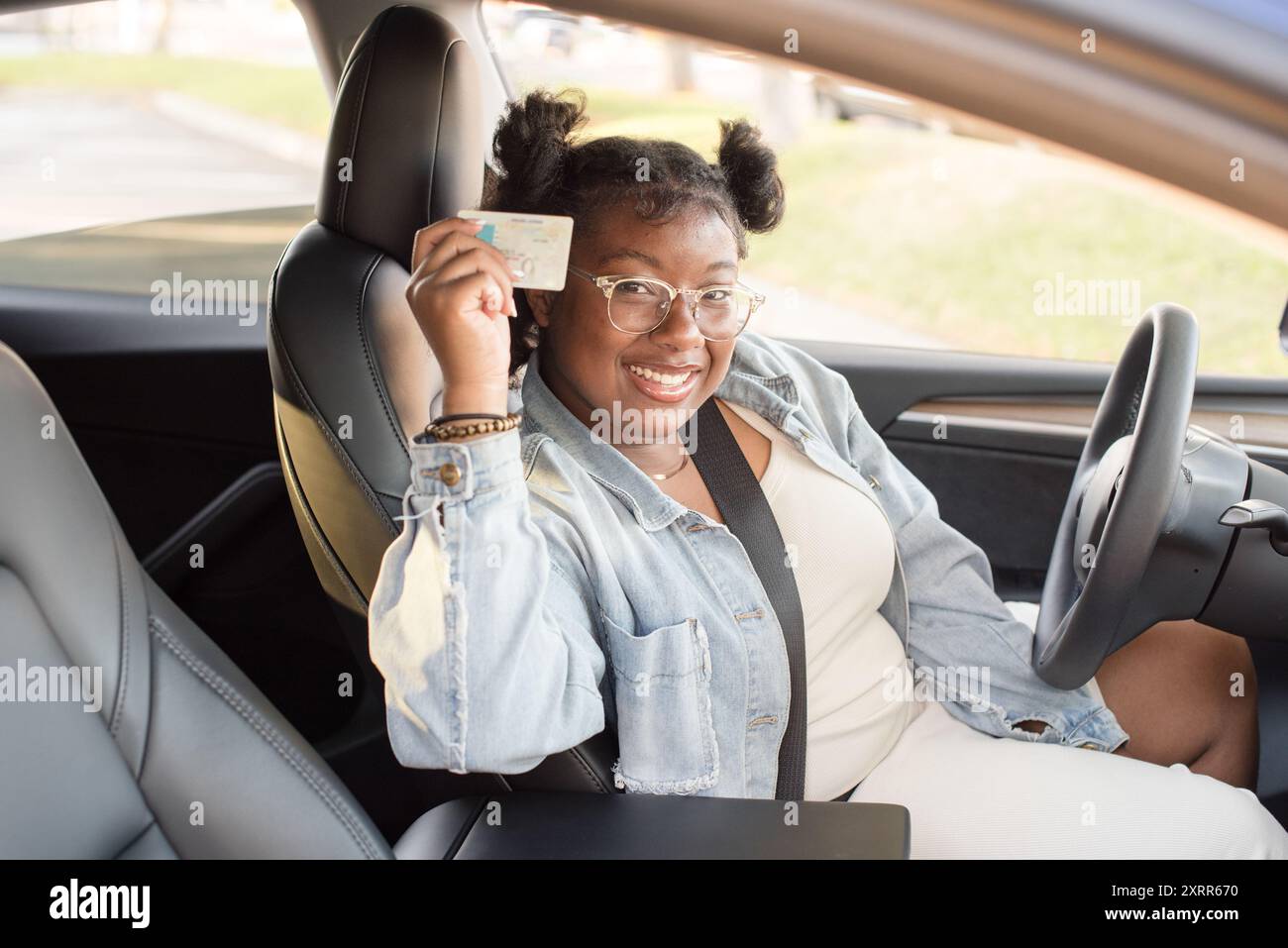 Young woman holding up a drivers license in a car Stock Photo - Alamy