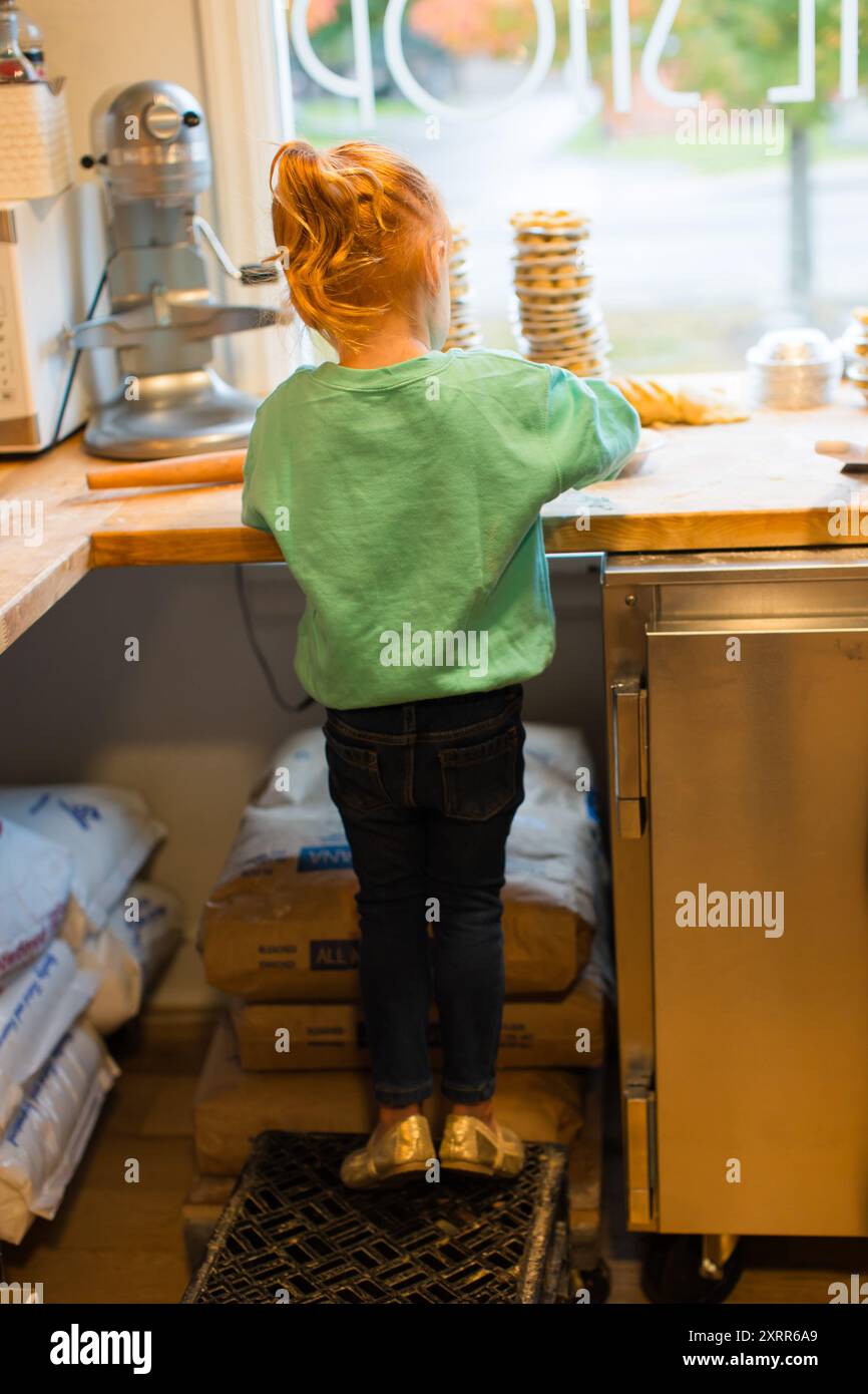 Little red headed girl standing on crate making pie Stock Photo - Alamy