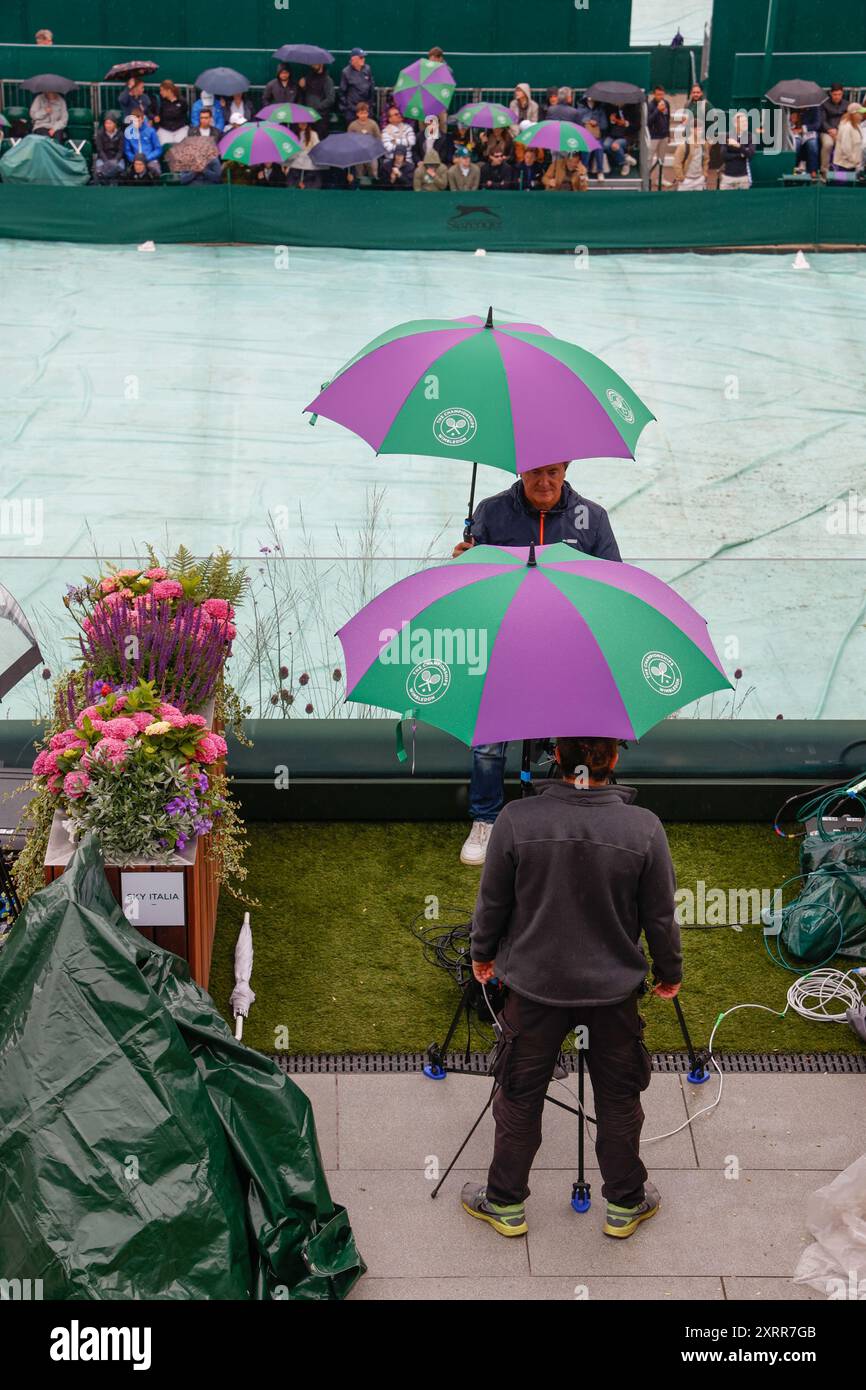 TV commentatori standing in the rain holding an umbrella on the media ...