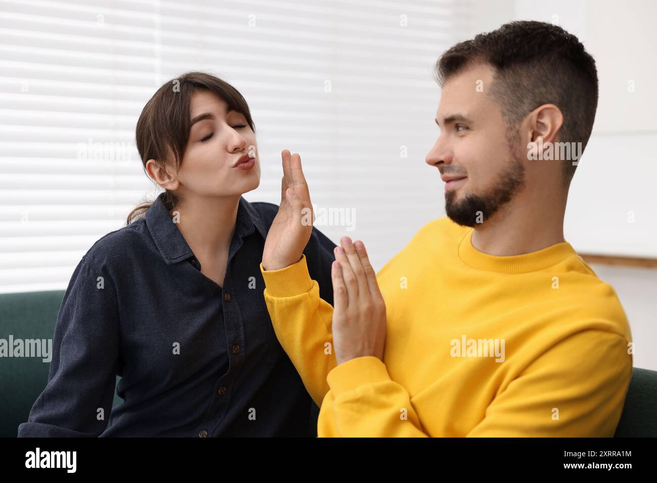 Embarrassed man refusing from woman's kiss at home Stock Photo - Alamy