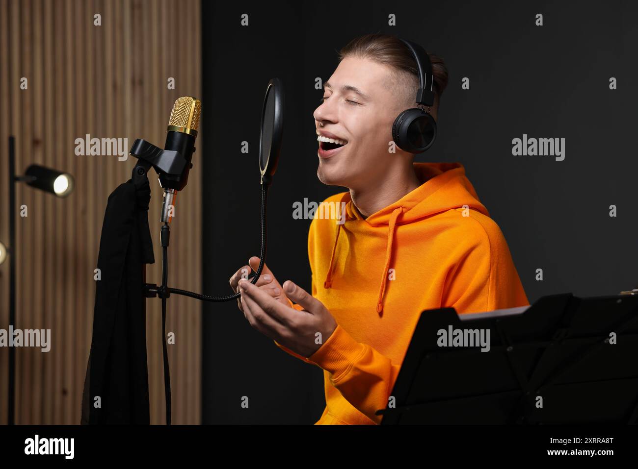 Man wearing headphones singing into microphone in professional record ...