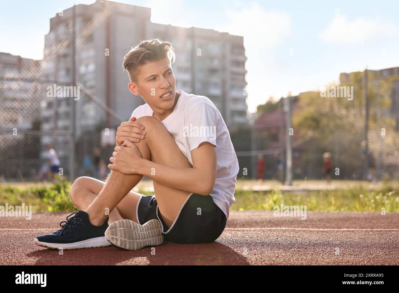 Sportsman with leg injury suffering from knee pain at stadium, space ...