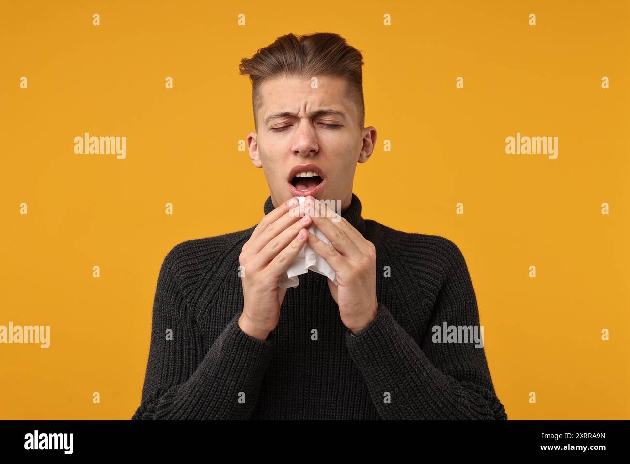 Sick man with tissue sneezing on orange background. Cold symptoms Stock ...