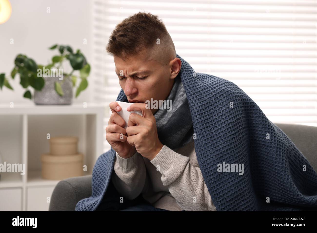 Cold symptom. Young man with runny nose at home Stock Photo - Alamy