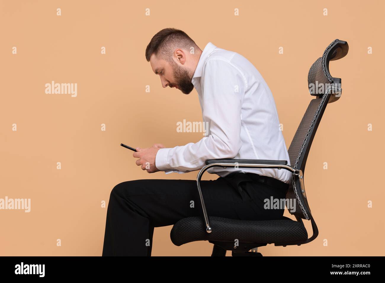 Man with poor posture sitting on chair and using smartphone against ...
