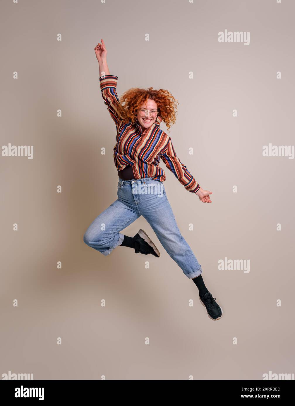 Crazy young woman with hand raised jumping in air and celebrating ...