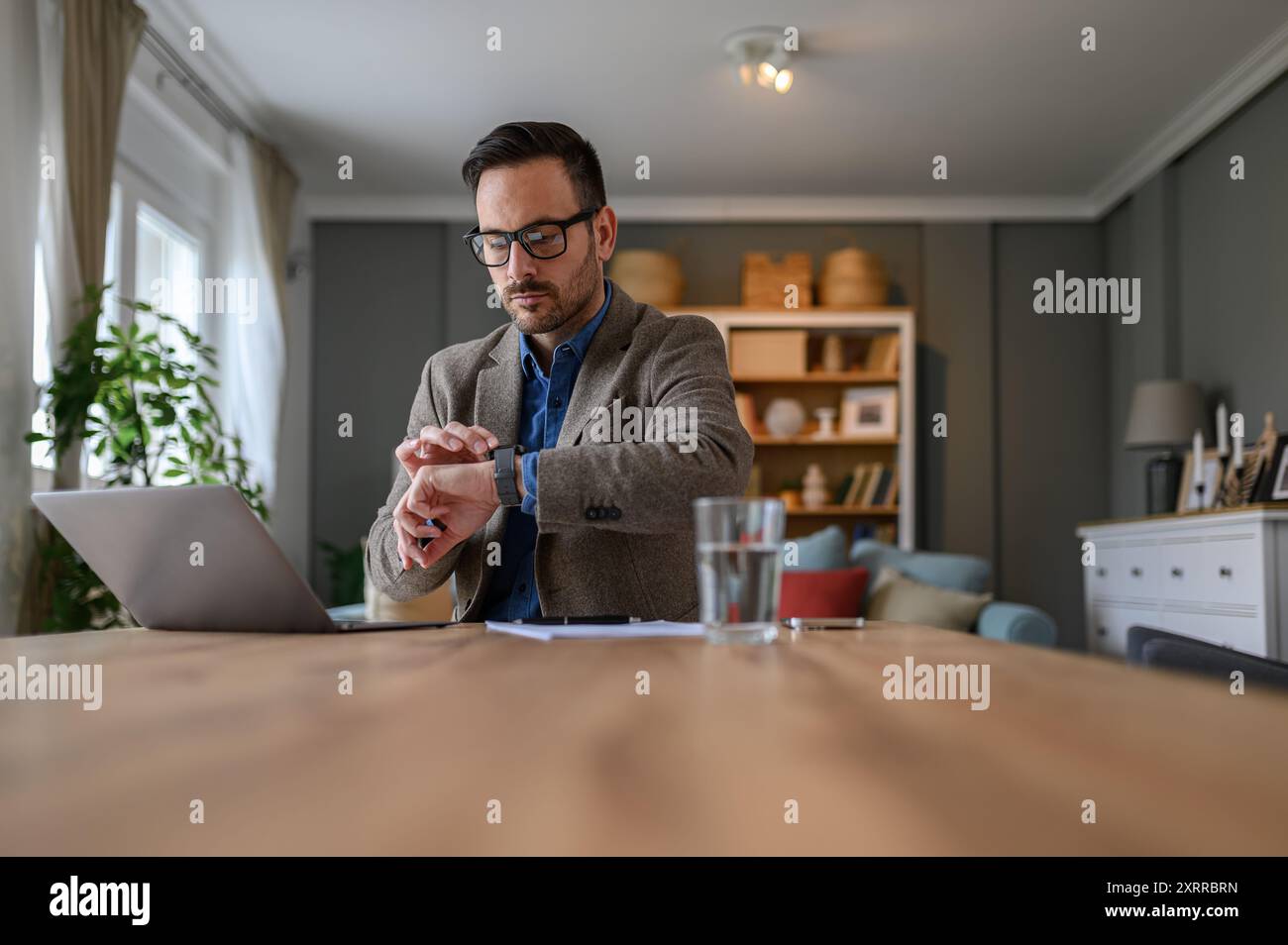 Portrait of serious businessman checking time on wristwatch while ...