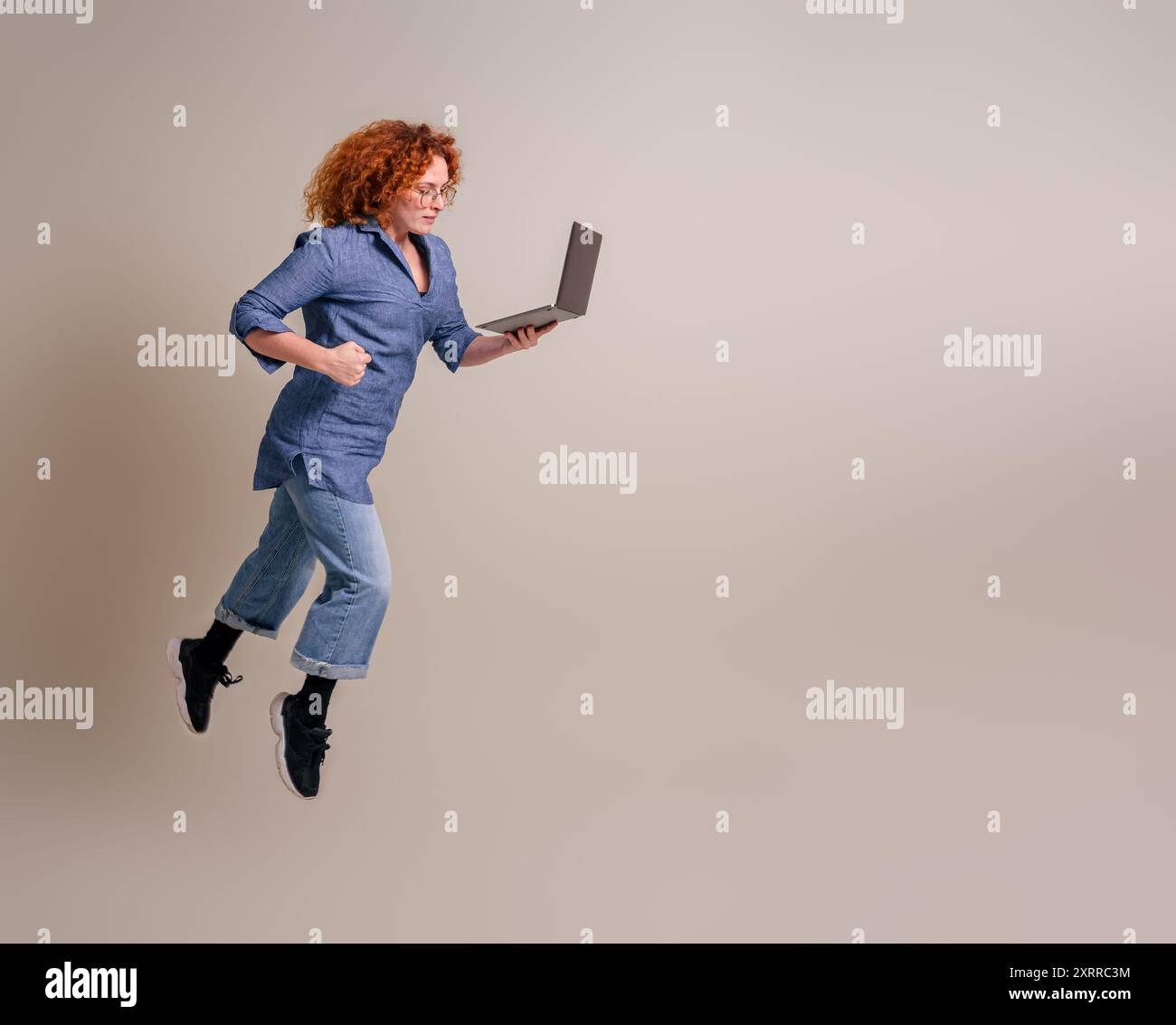 Inspired female manager with laptop jumping in air and celebrating ...