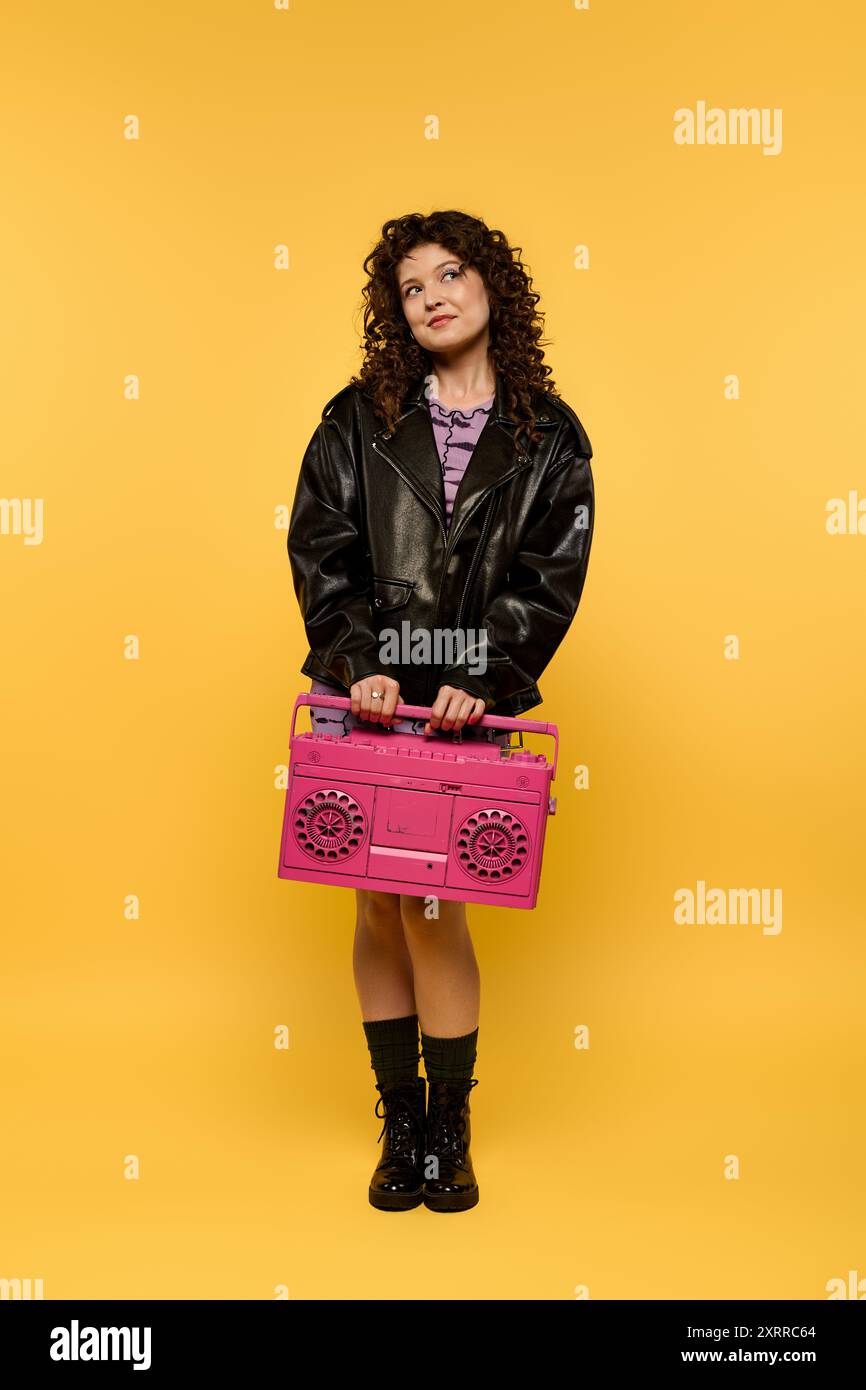 A young woman with curly hair poses in a black leather jacket while ...
