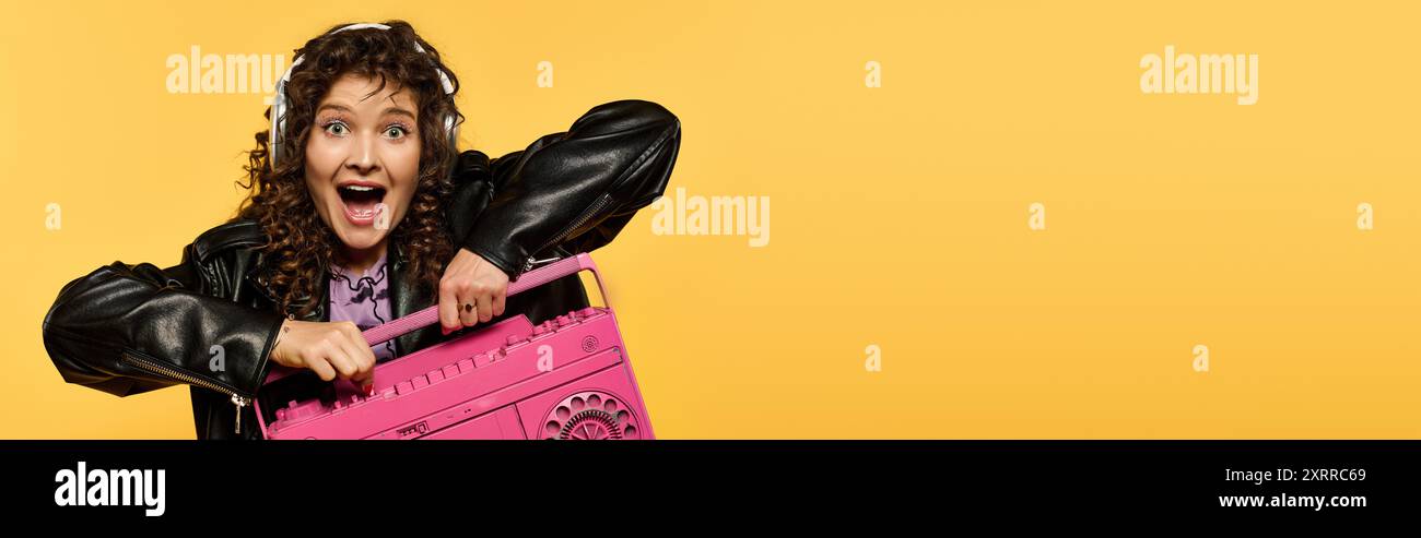 A young woman in a black leather jacket and headphones poses with a ...