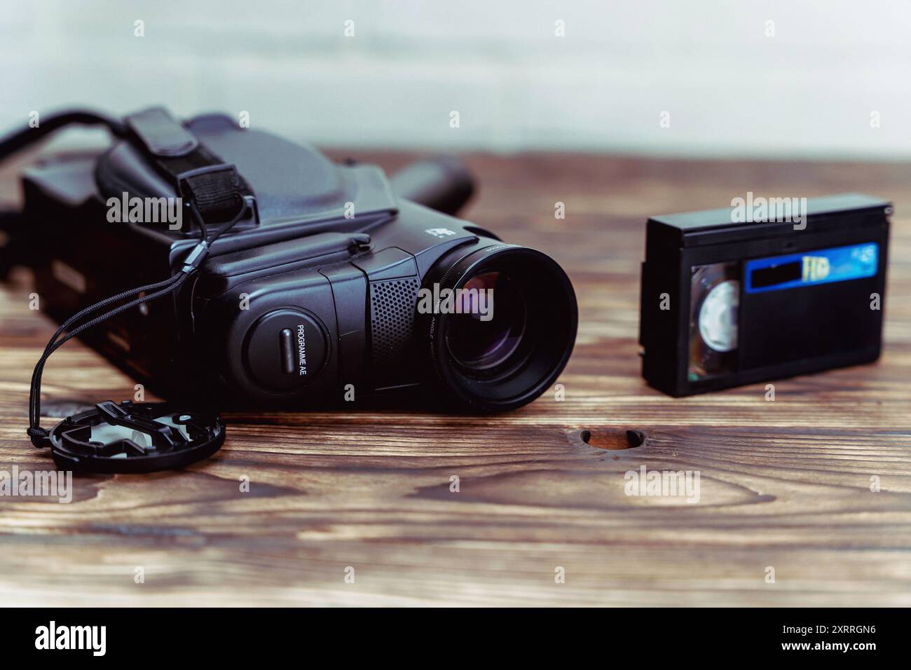 A vintage analog VHS video camera and a cassette with film on a wooden ...