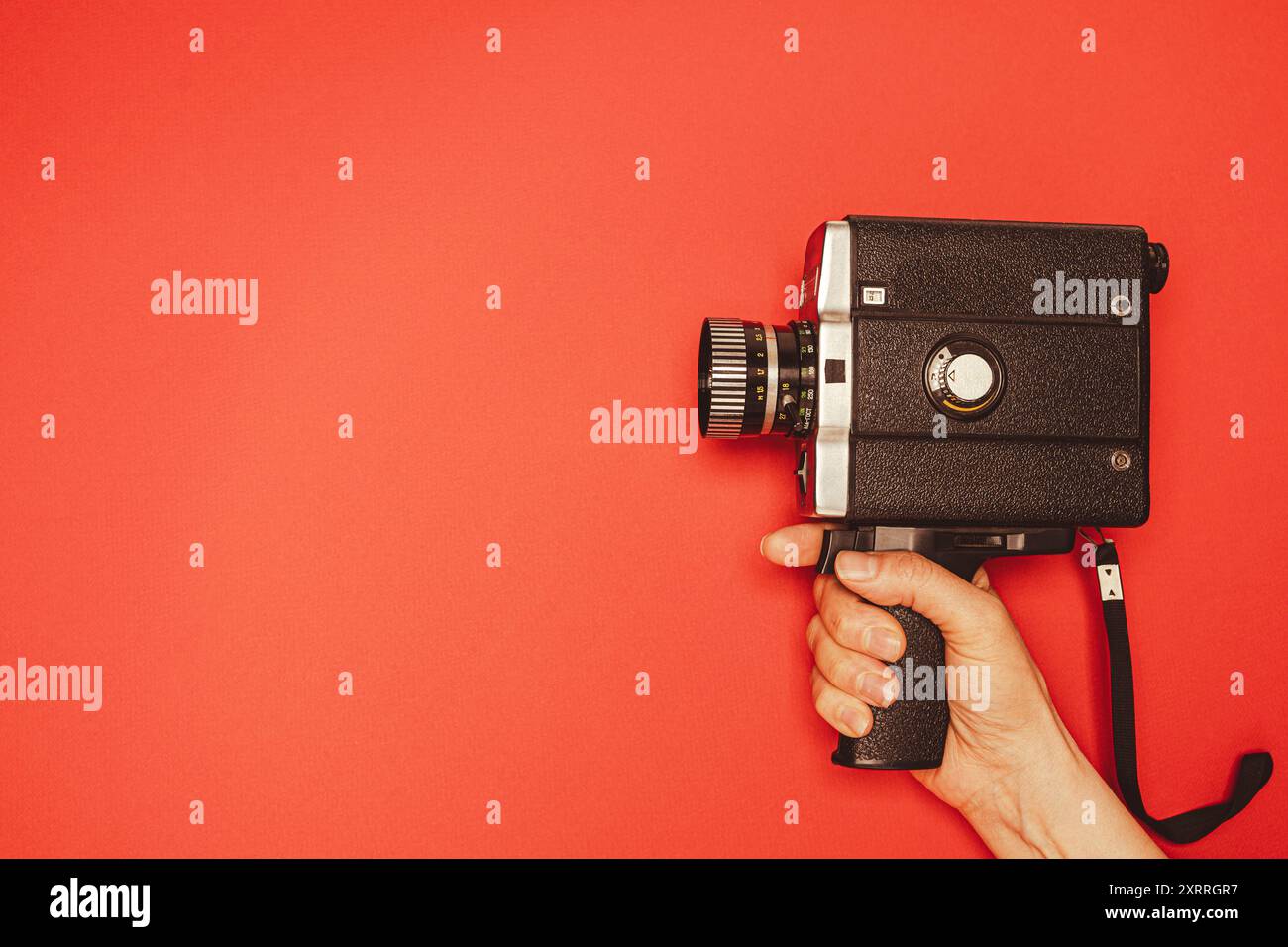 vintage portable movie camera in a woman's hand on a red background ...