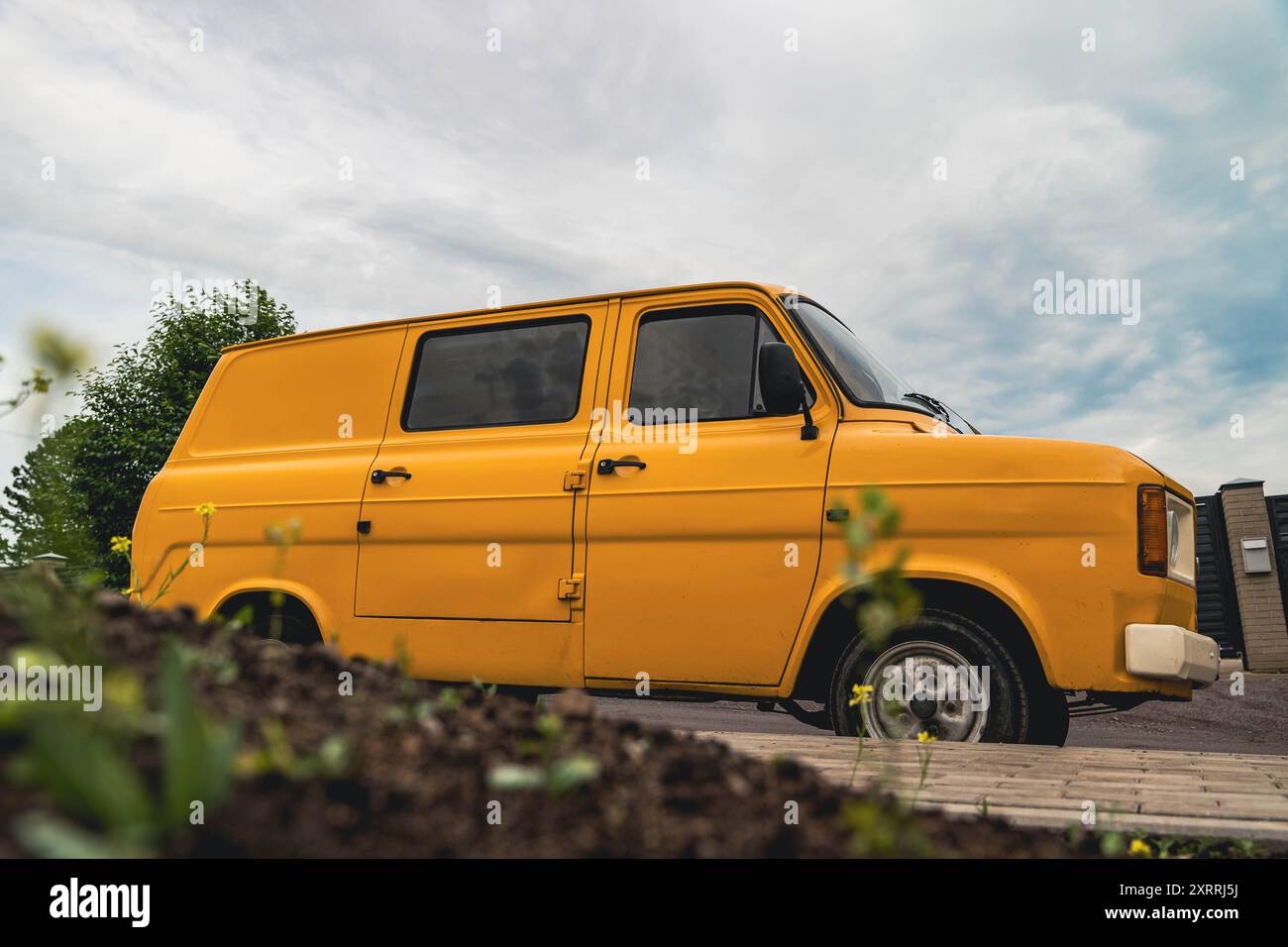 A yellow van parked on a paved street Stock Photo - Alamy