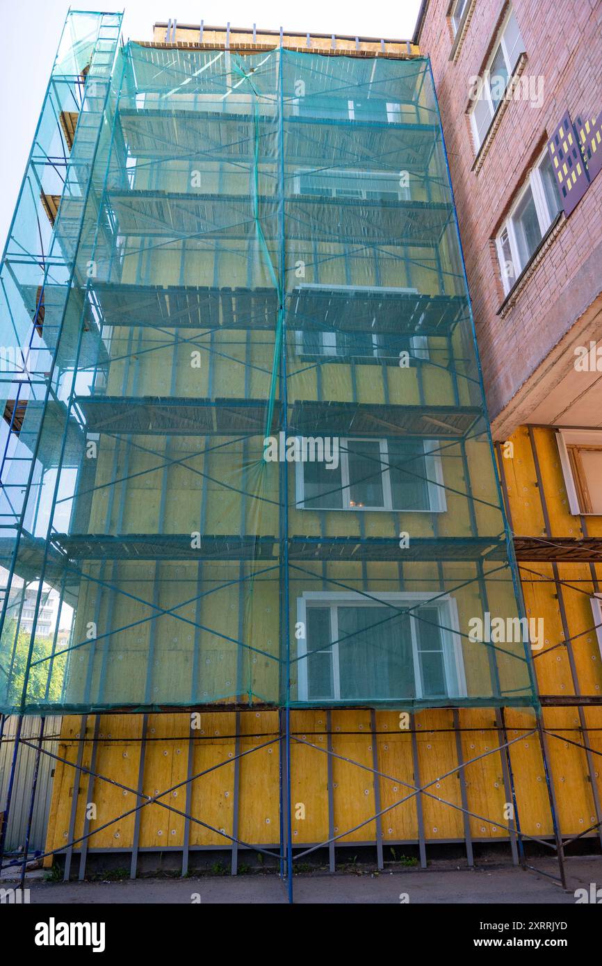 Building facade under renovation with scaffolding and green netting ...
