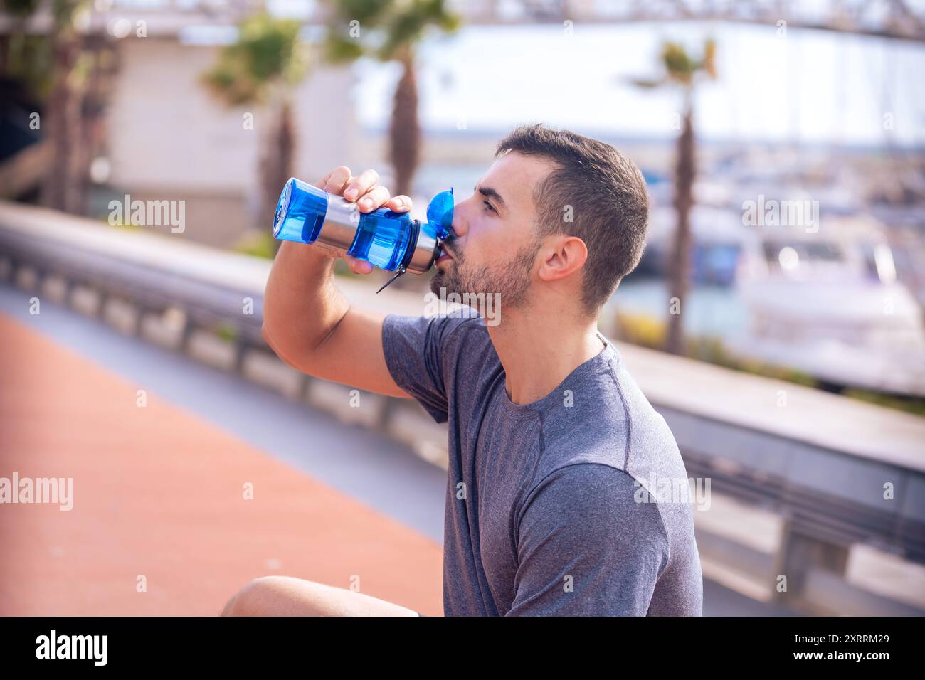 Side view runner man drinking water from a sports bottle outdoors Stock ...