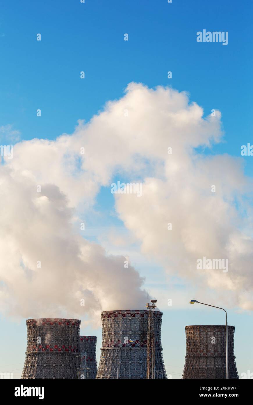 Industrial cooling towers emitting steam into sky against clear blue ...