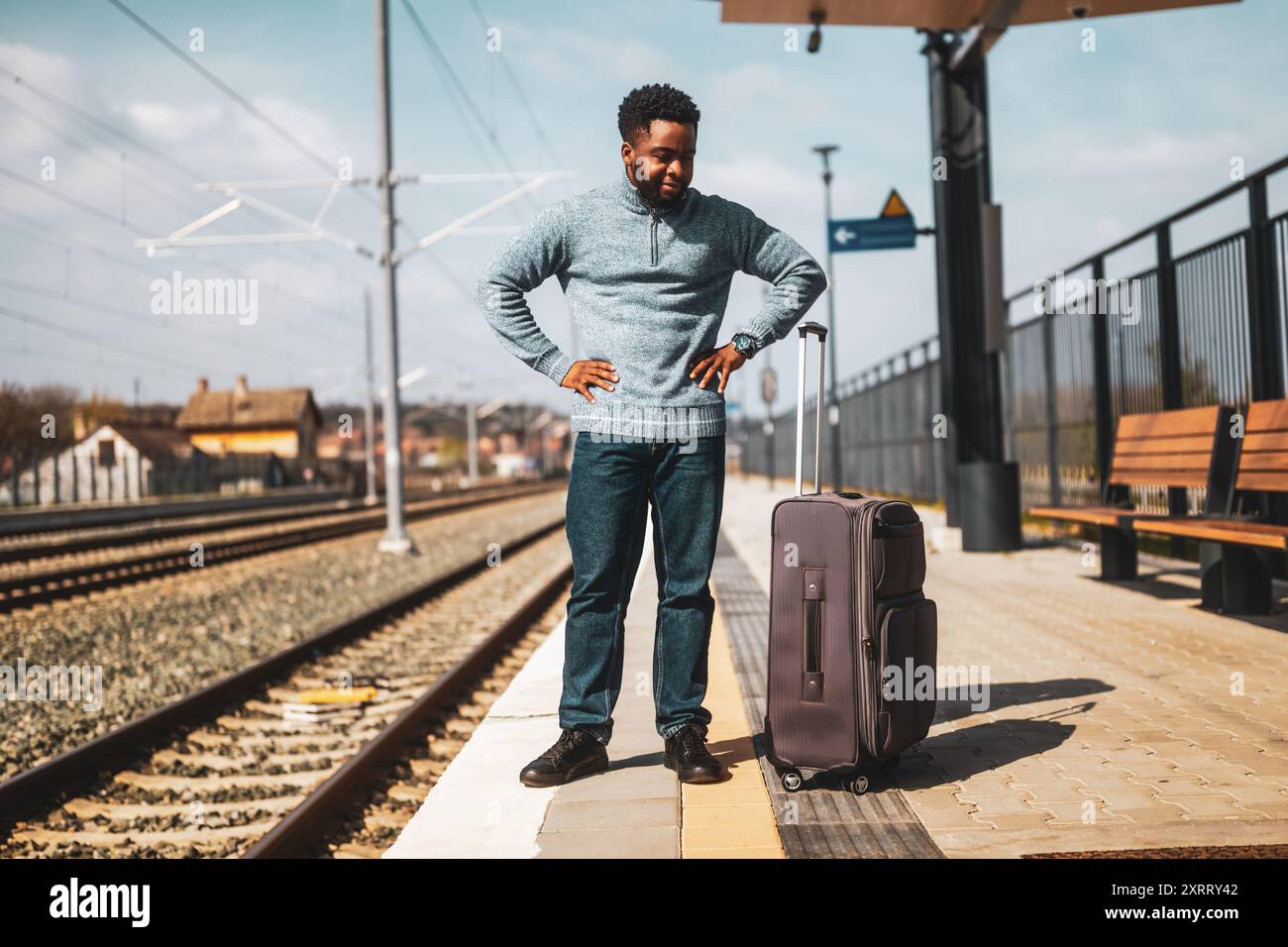 Angry man with a suitcase standing on a railway station Stock Photo - Alamy