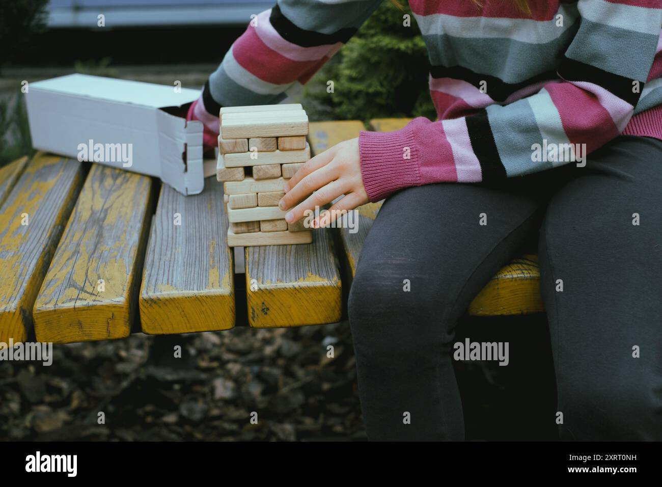 Preschool girl carefully balances wooden block with her fingers during ...