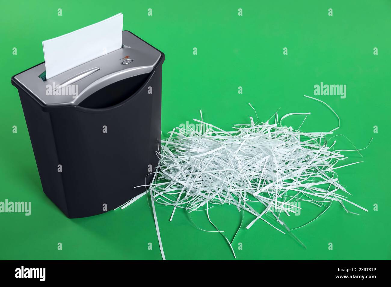 Shredder and pile of paper strips on green background Stock Photo - Alamy