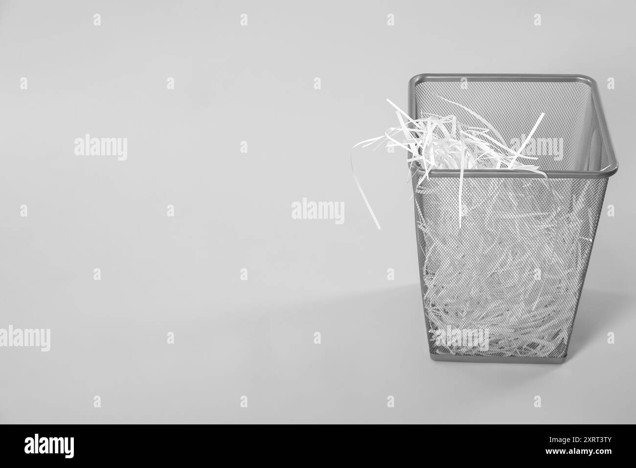 Shredded paper strips in trash bin on light grey background, space for ...