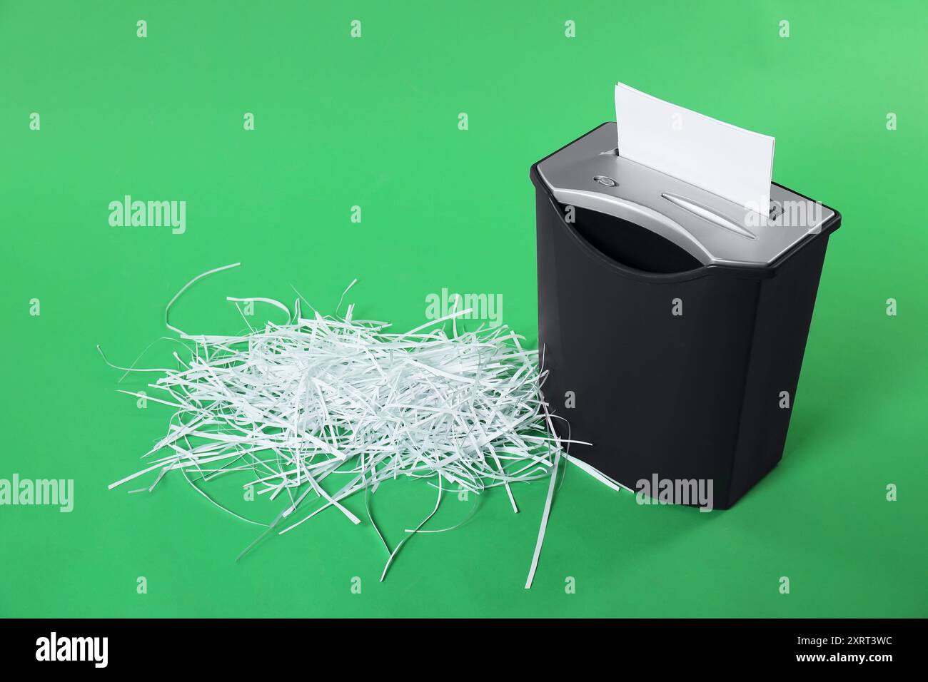 Shredder and pile of paper strips on green background Stock Photo - Alamy