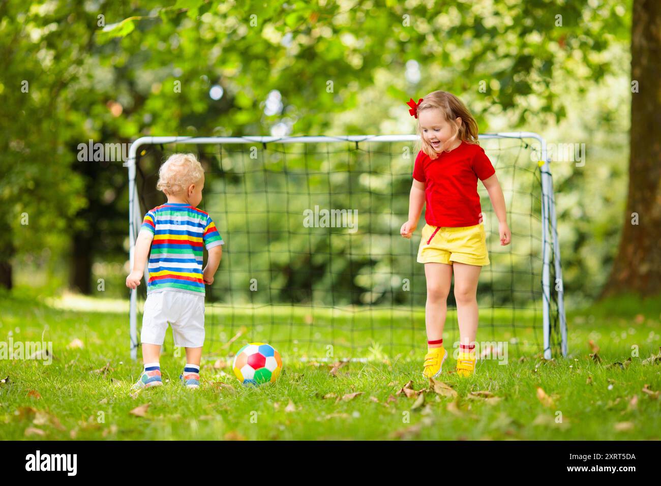 Child playing football. Kids play soccer on outdoor pitch. Little boy ...
