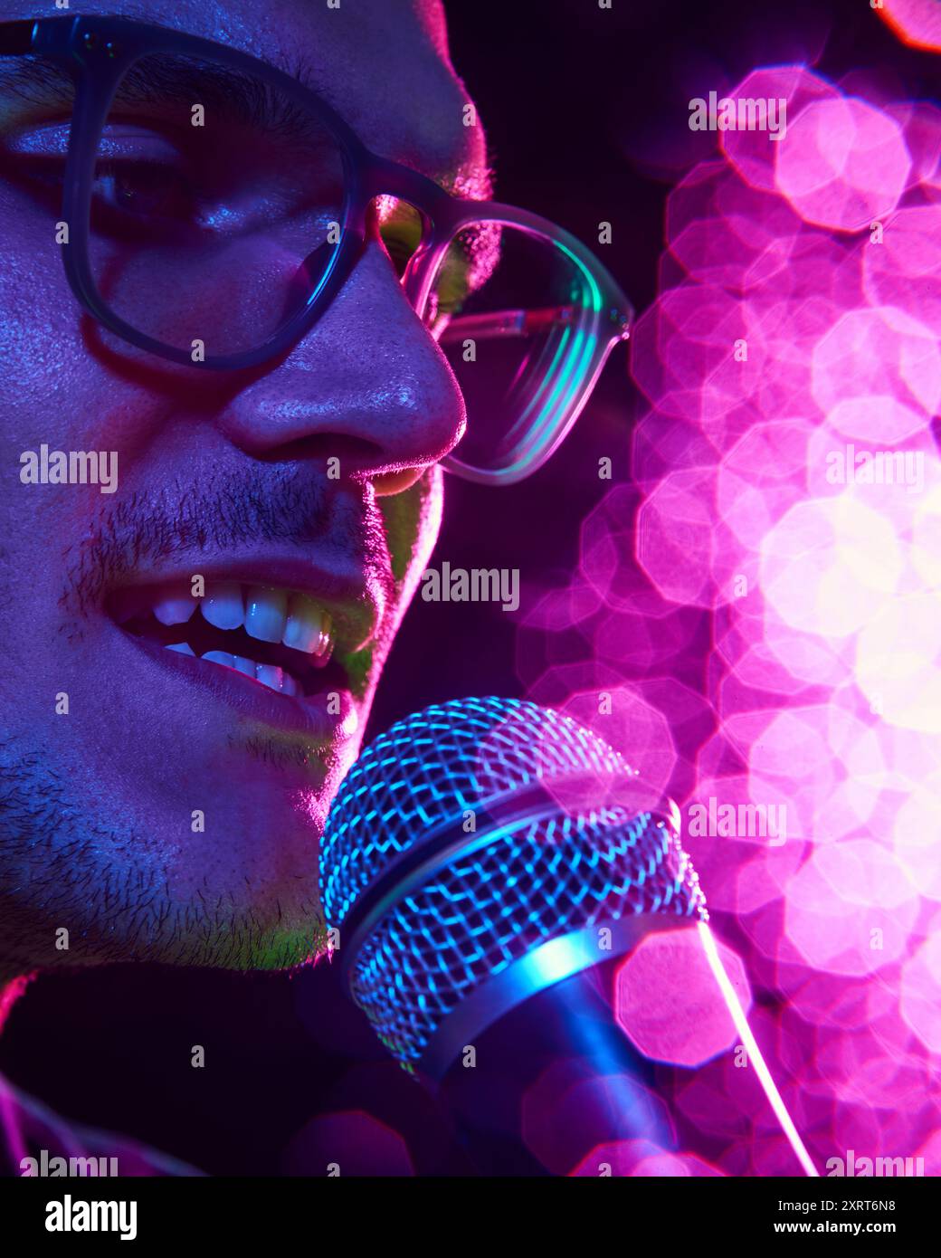 Close-up photo of singer's face, bathed in colorful stage lights ...