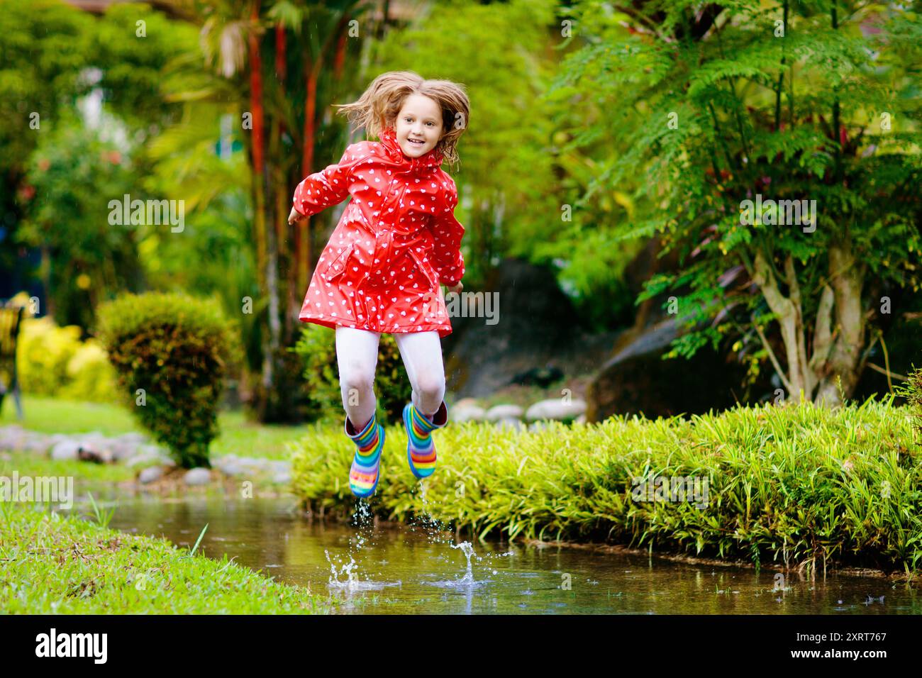 Child playing in puddle. Kids play and jump outdoor by autumn rain ...