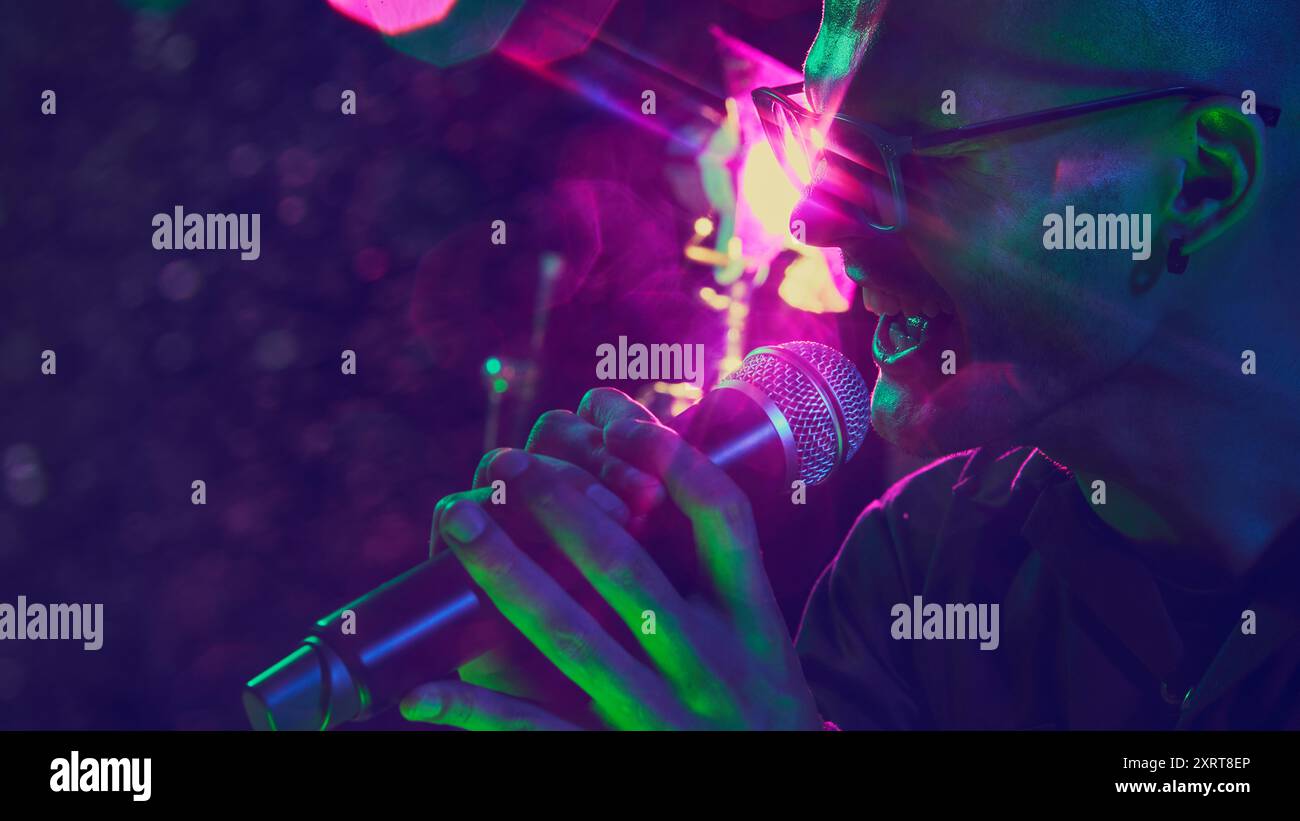 Vivid glow of stage lights casts dramatic shadow on singer's face ...