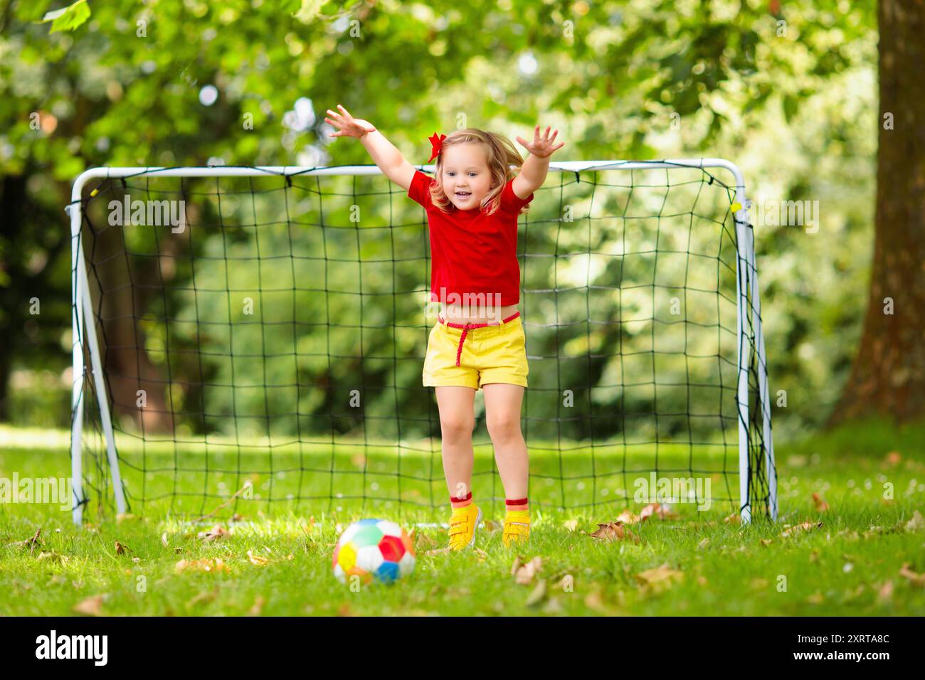 Child playing football. Kids play soccer on outdoor pitch. Little boy ...