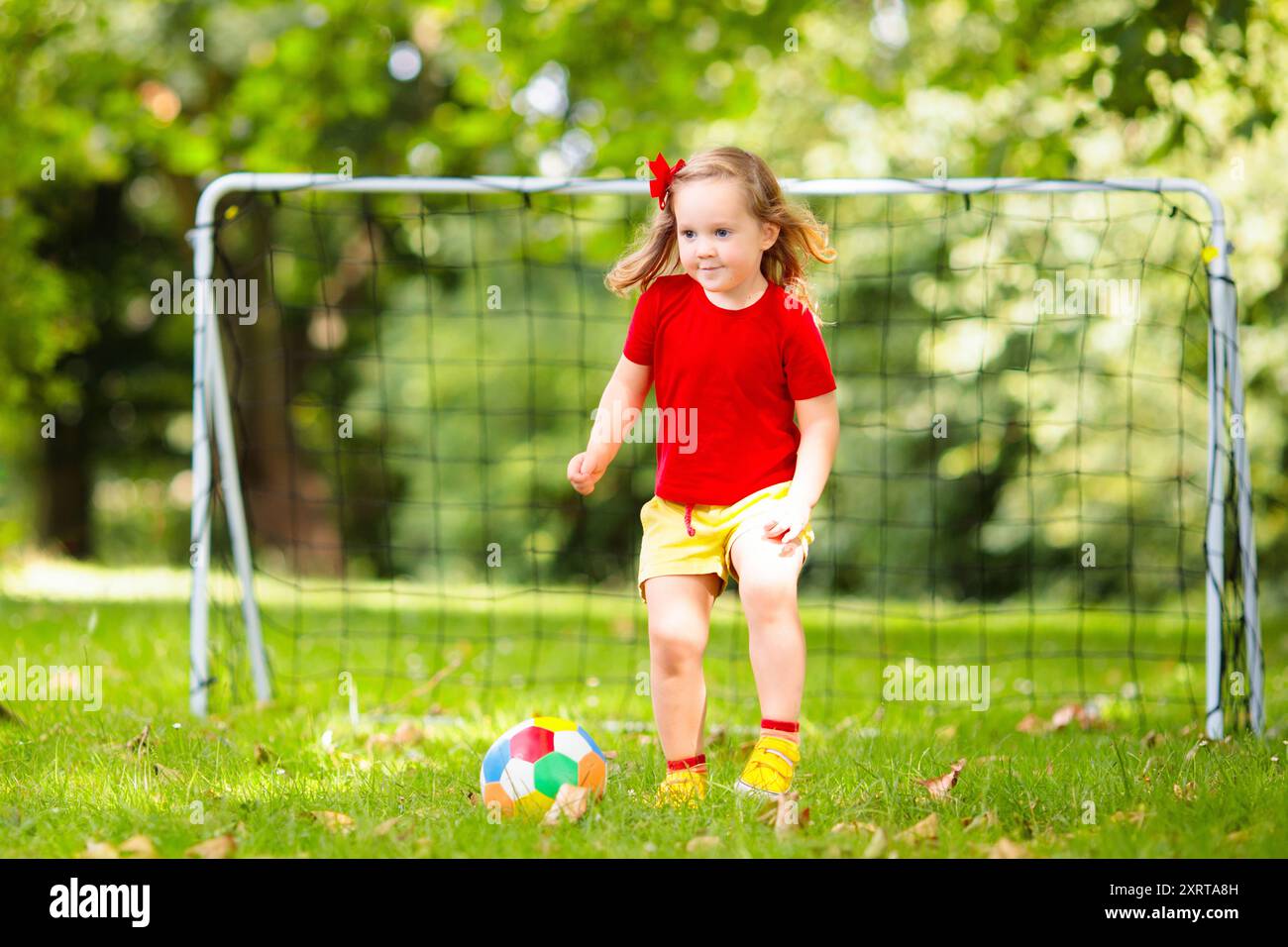 Child playing football. Kids play soccer on outdoor pitch. Little boy ...