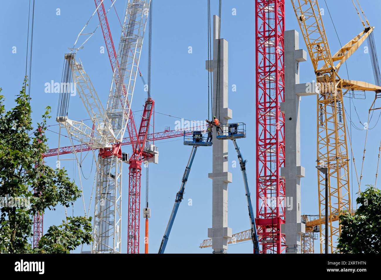 Eine neue Fabrikhalle entsteht. Montagearbeiter zwischen Baukränen ...