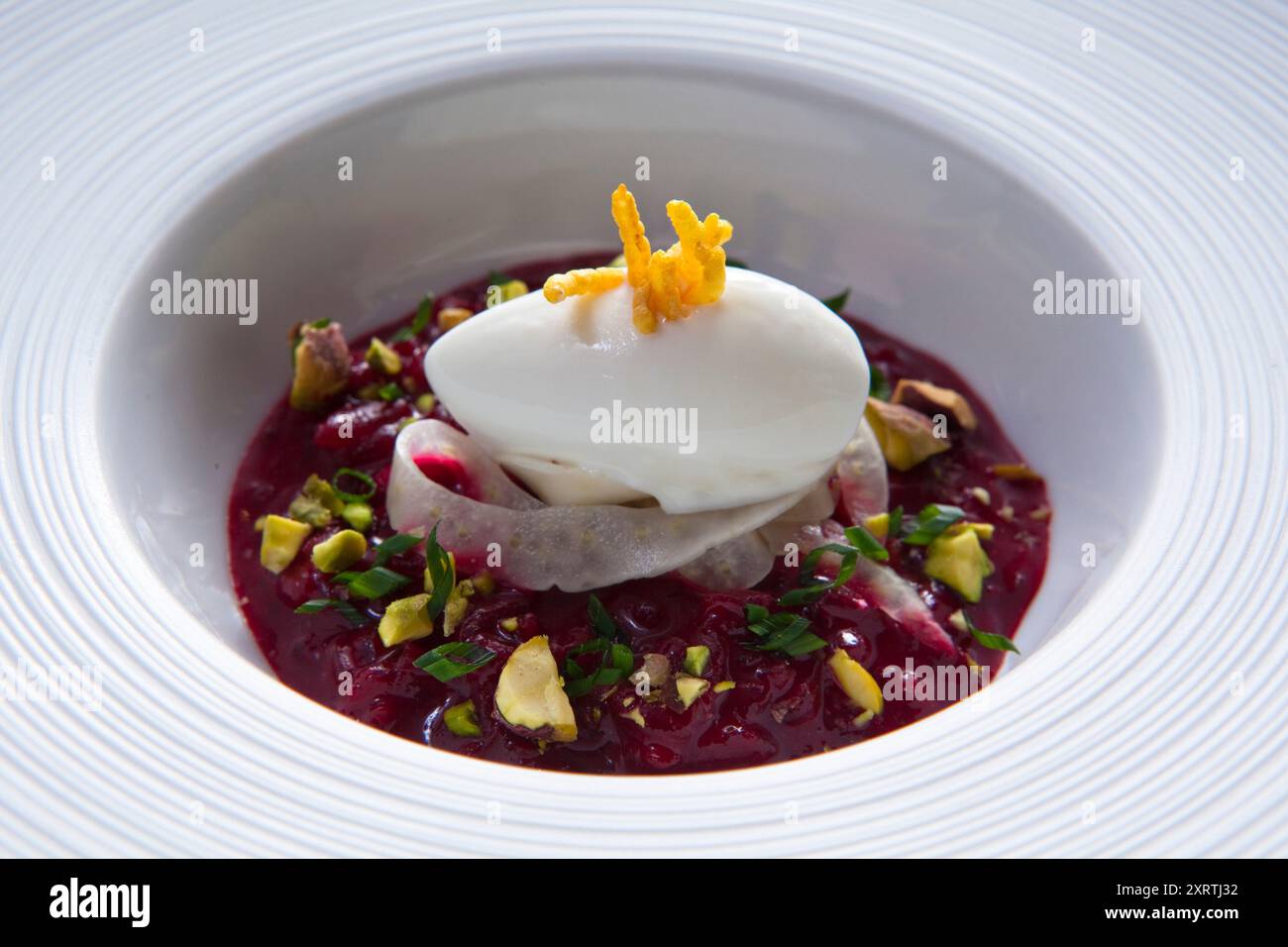 A large white bowl full of Beetroot risotto topped with beetroot cream ...