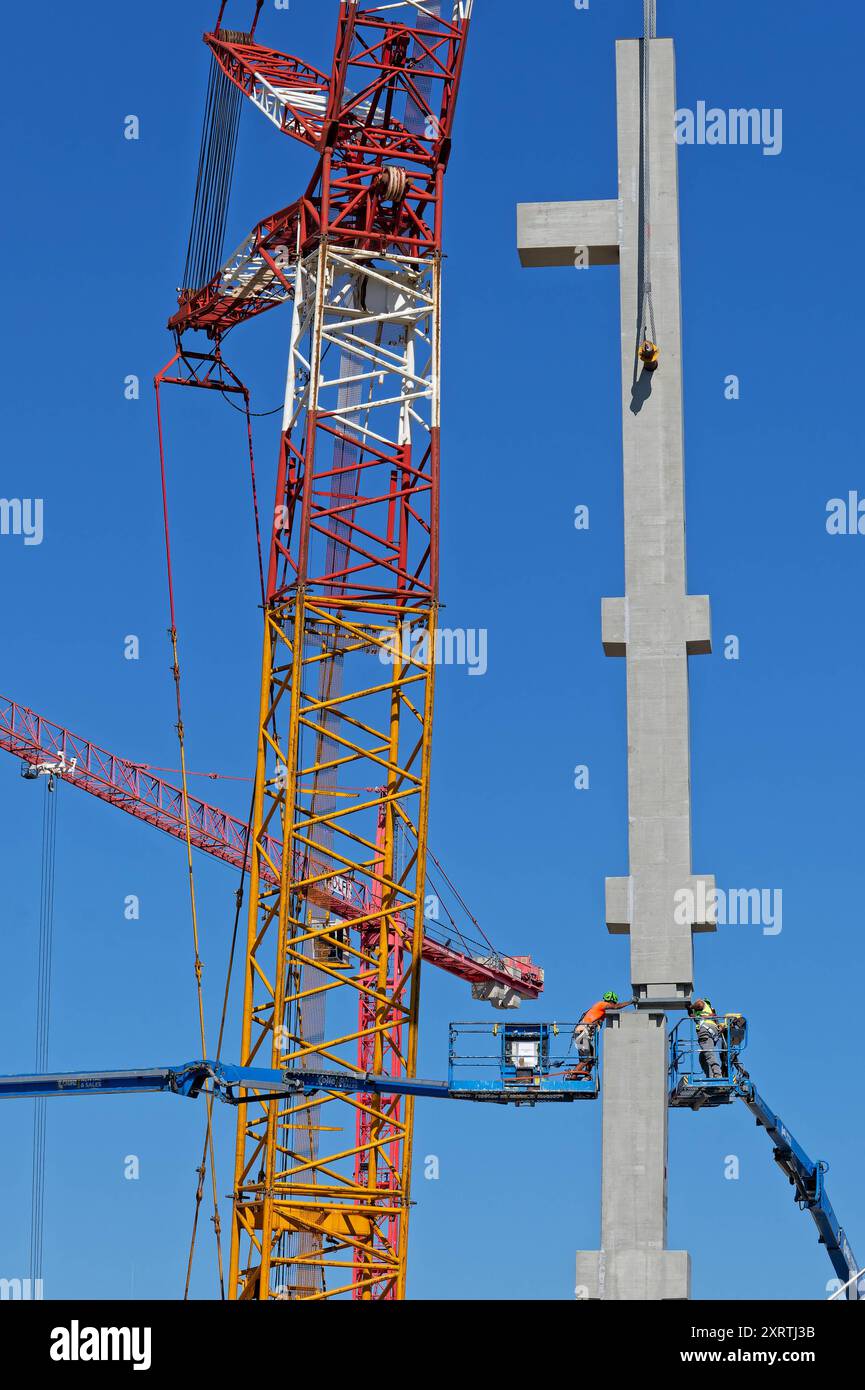 Eine neue Fabrikhalle entsteht. Montagearbeiter zwischen Baukränen ...