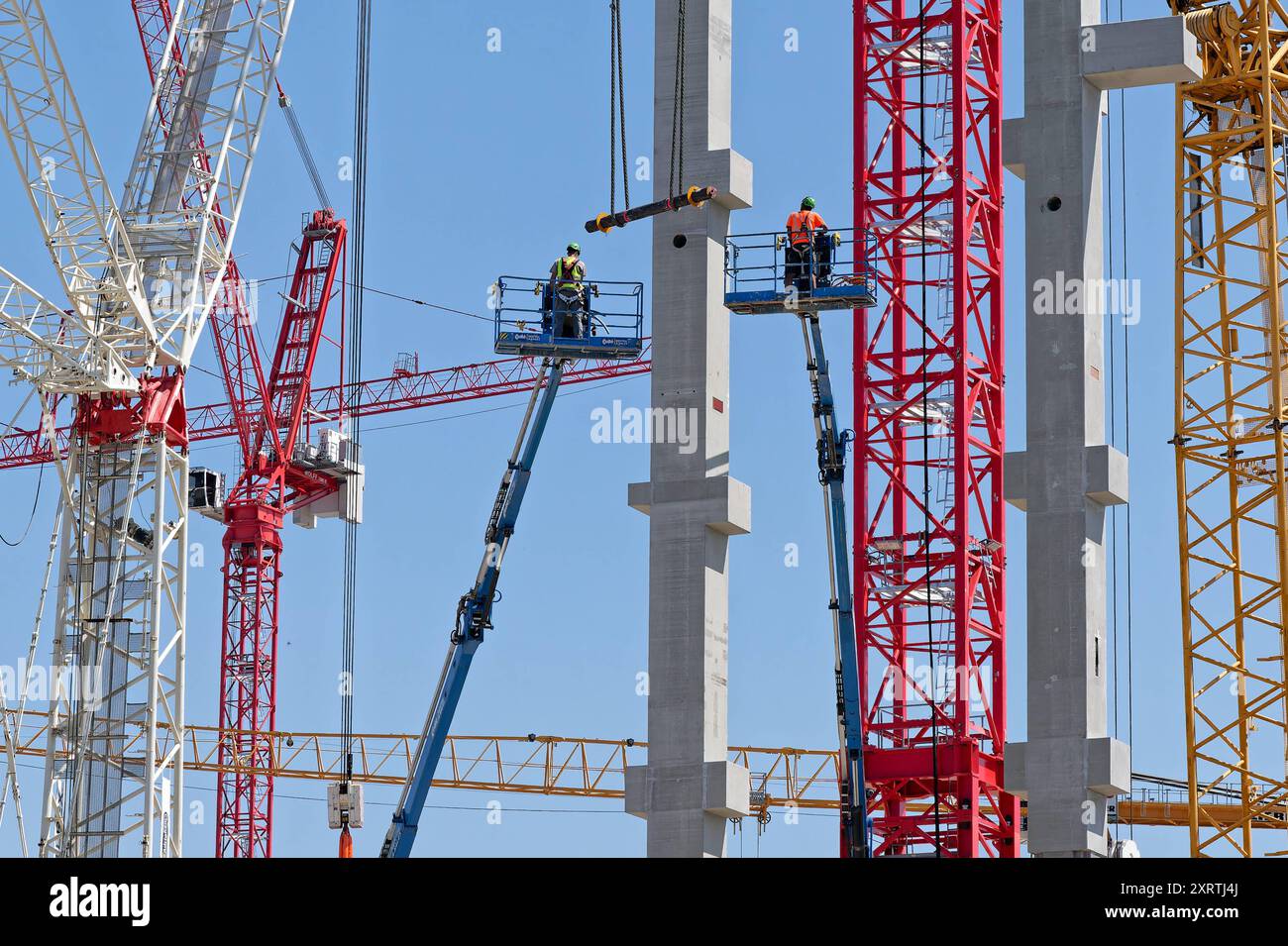 Eine neue Fabrikhalle entsteht. Montagearbeiter zwischen Baukränen ...