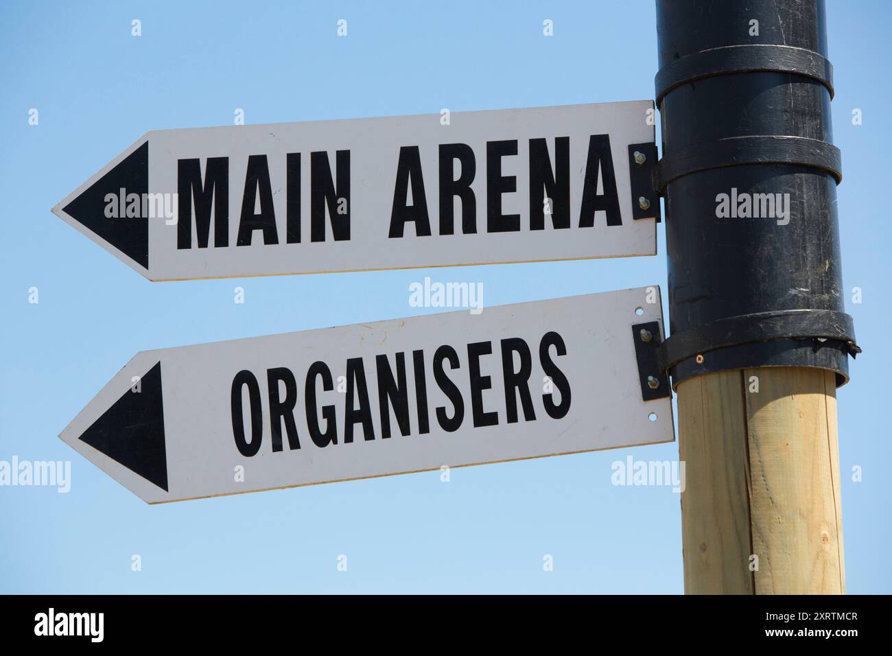 A wooden post at an outdoor event with signs to the arena Stock Photo ...