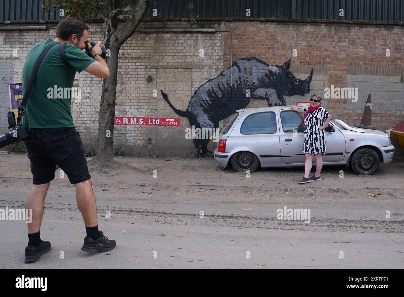 A woman poses for a photograph by a new artwork unveiled by Banksy ...