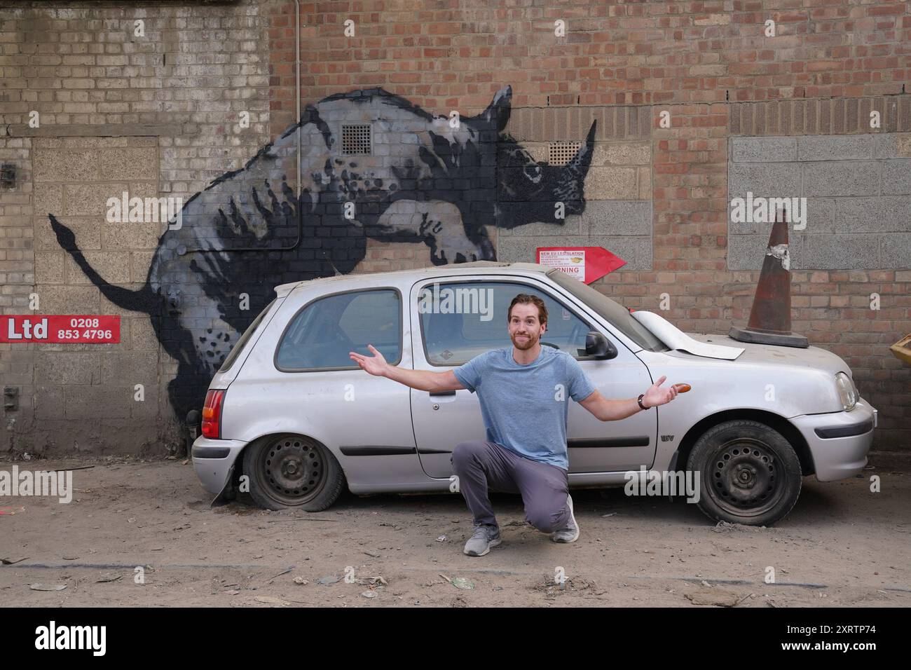 A man poses for a photograph by a new artwork unveiled by Banksy ...