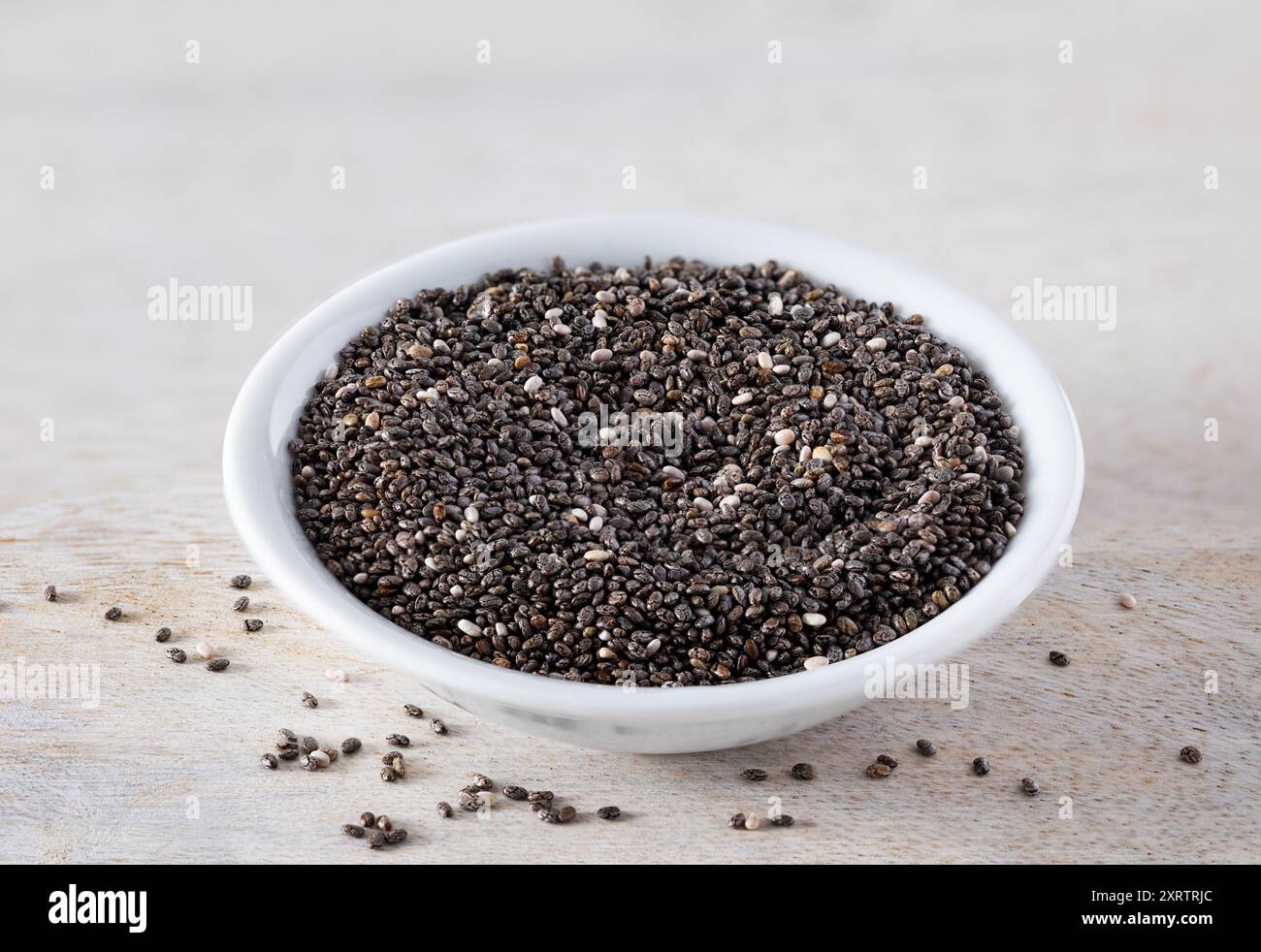 Close-up of black chia seed in a small white container on a light ...