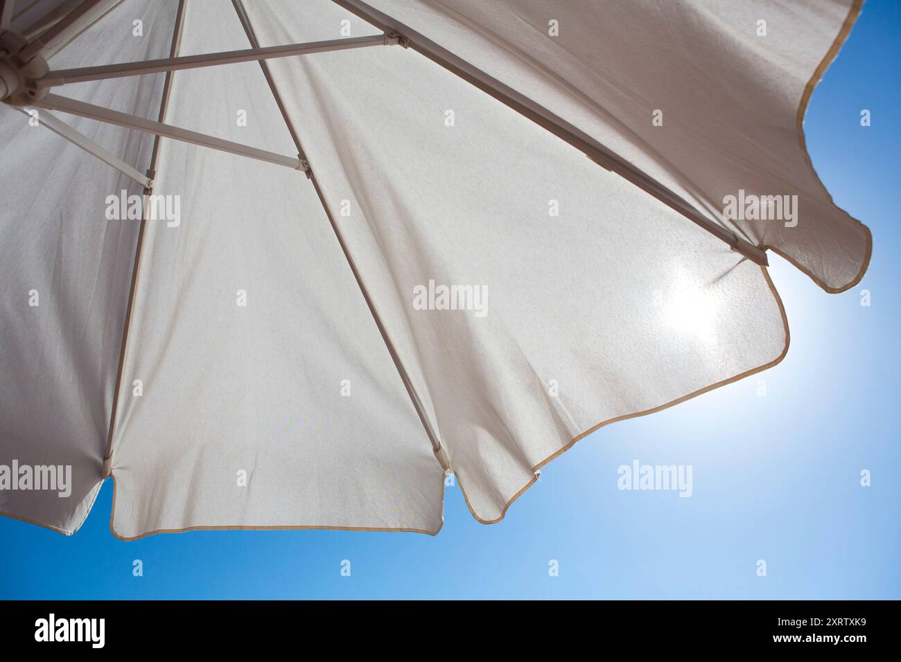 A large canvas umbrella protecting the sitter below from the harsh ...