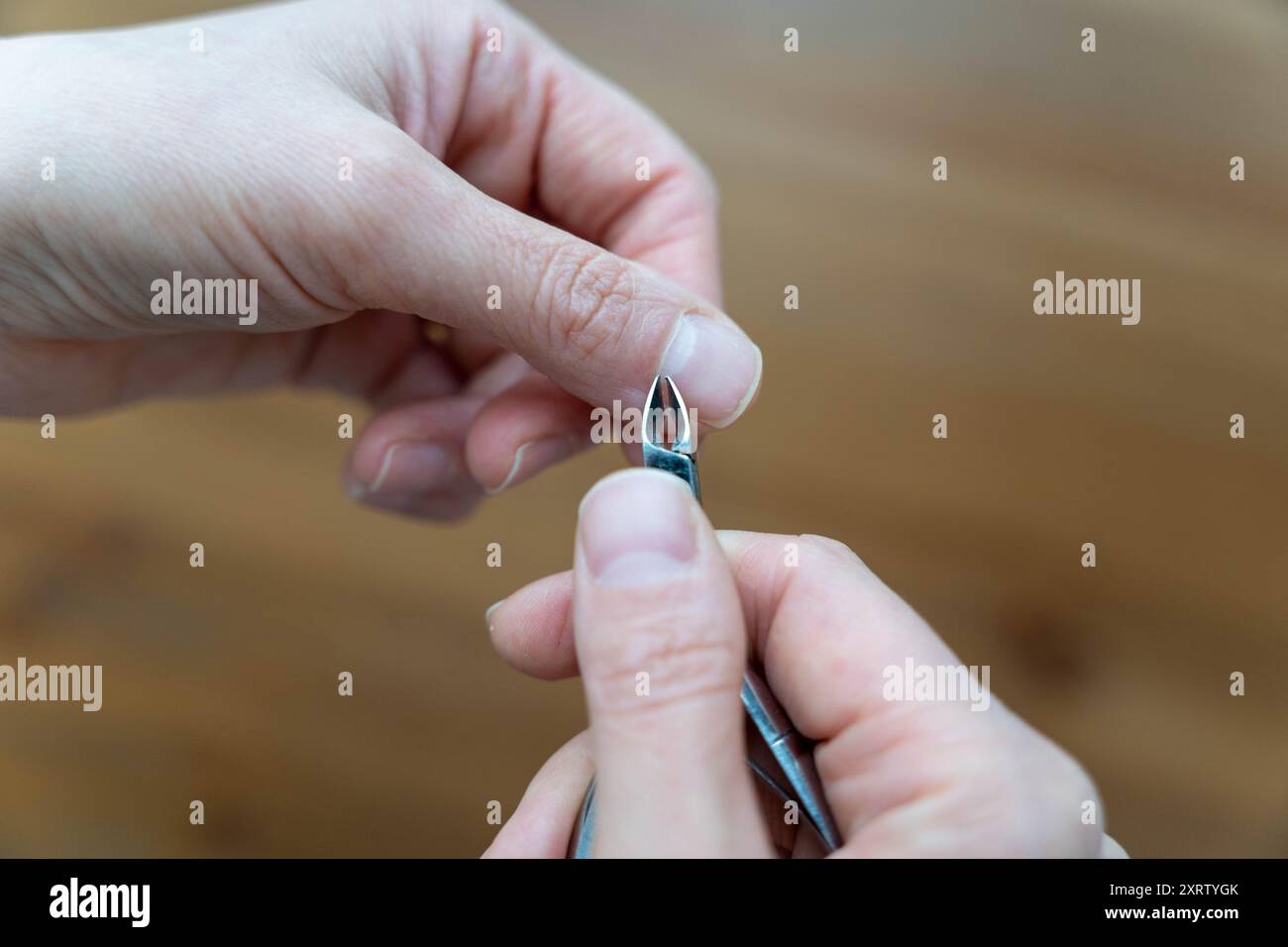 women's hands do manicures by trimming cuticles with nail clippers ...
