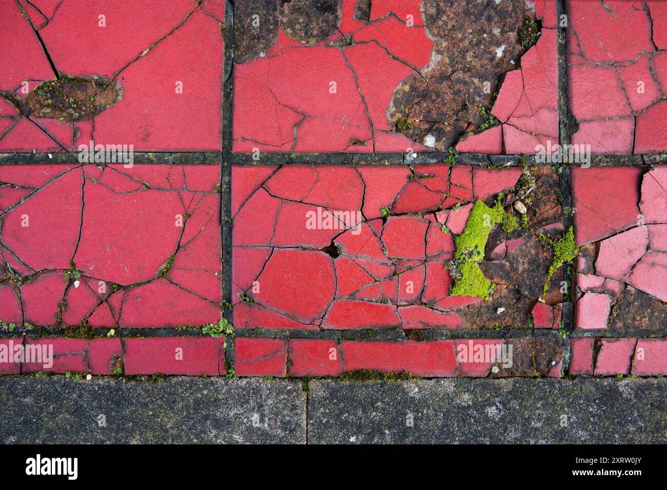 Looking down on broken red ceramic floor tiles cracked and weathered on ...