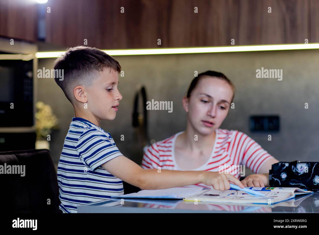 Mother helping her son doing homework in kitchen Stock Photo - Alamy