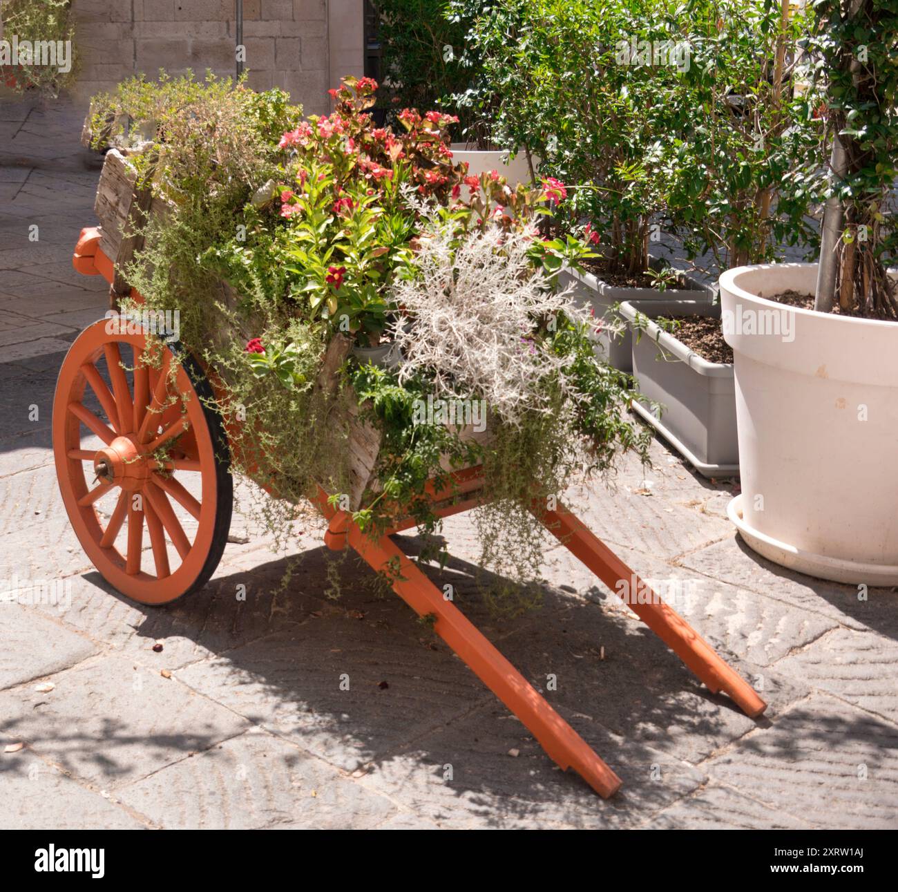 Rustic horse drawn wheeled red cart in a stone square full bright ...