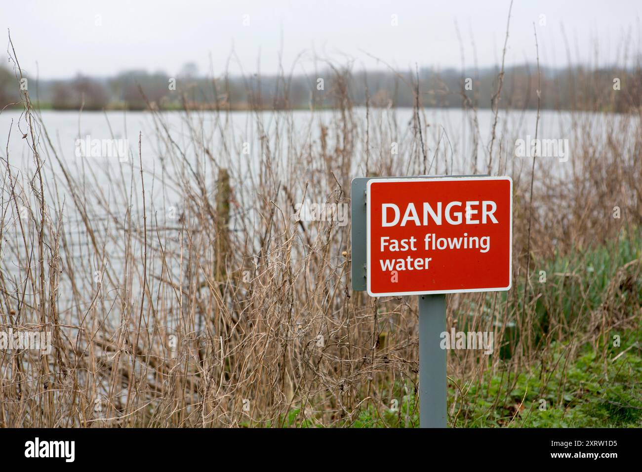 A red warning sign on a post by a fast flowing river Stock Photo - Alamy